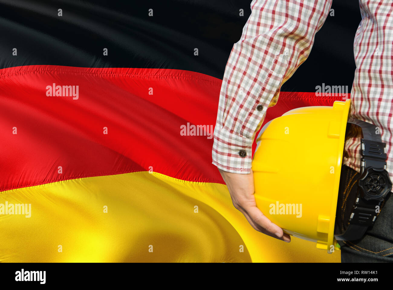 German Engineer is holding yellow safety helmet with waving Germany ...
