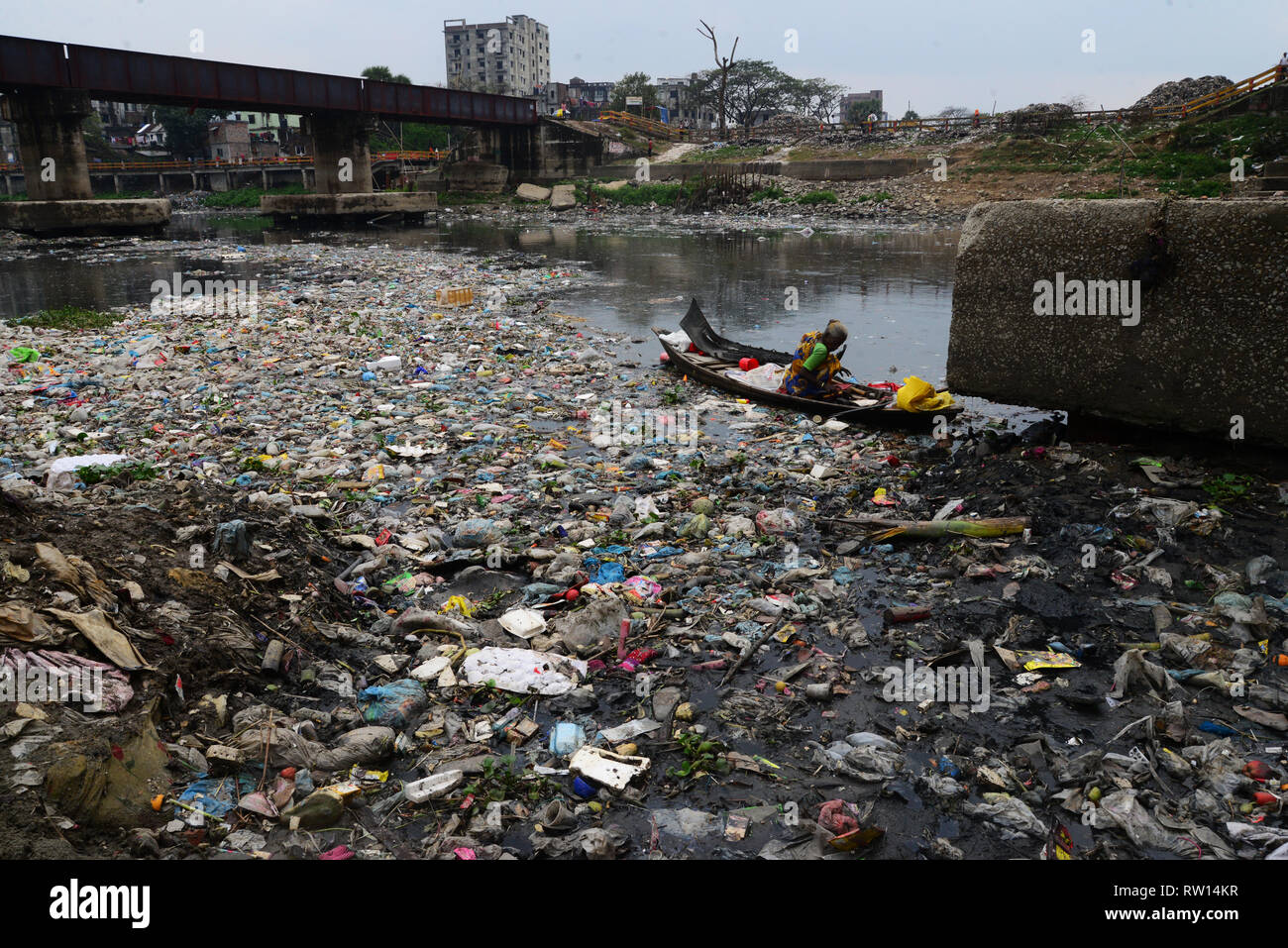 A Bangladesh woman collects plastic from the polluted Turag River in ...