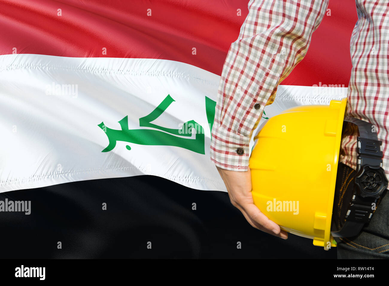 Iraqi Engineer is holding yellow safety helmet with waving Iraq flag ...