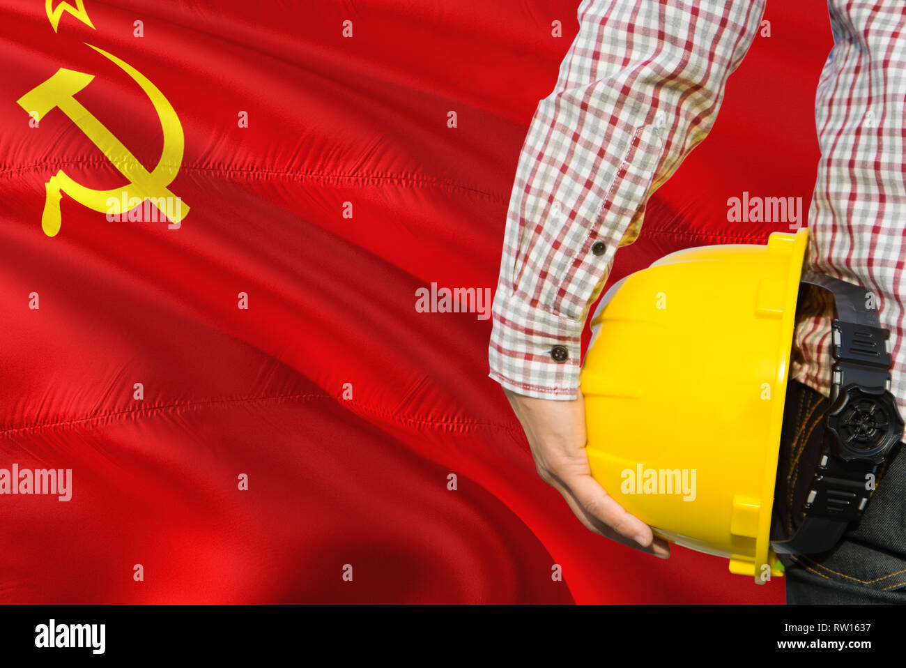 Engineer is holding yellow safety helmet with waving Soviet Union flag ...