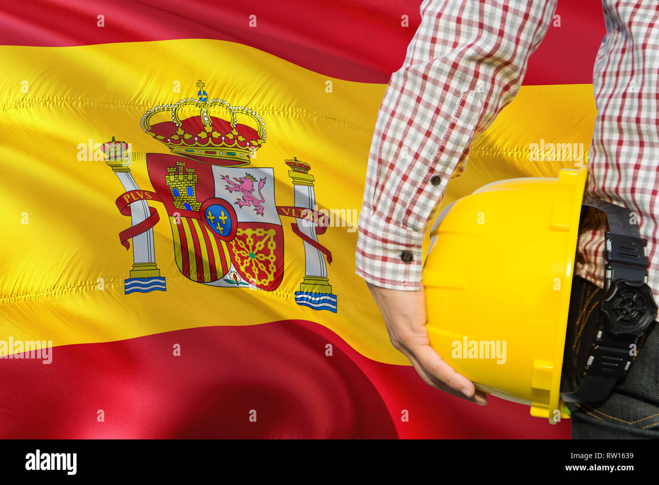 Spanish Engineer is holding yellow safety helmet with waving Spain flag ...