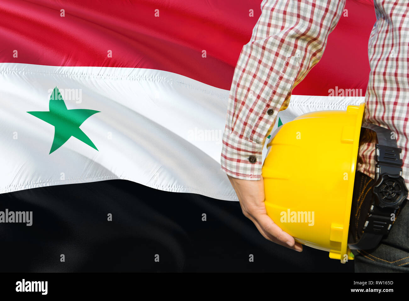 Syrian Engineer is holding yellow safety helmet with waving Syria flag ...