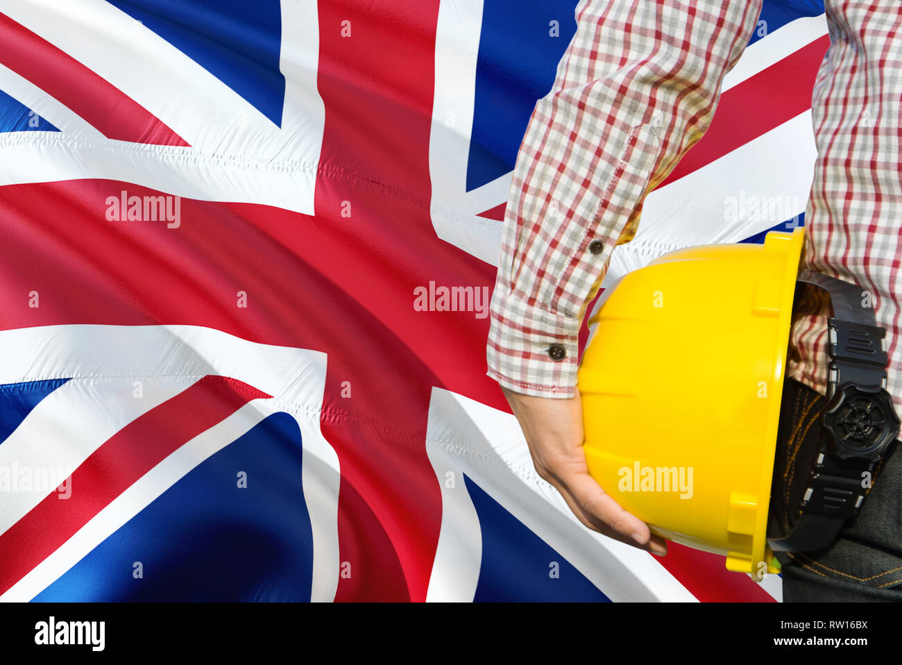 British Engineer is holding yellow safety helmet with waving United ...