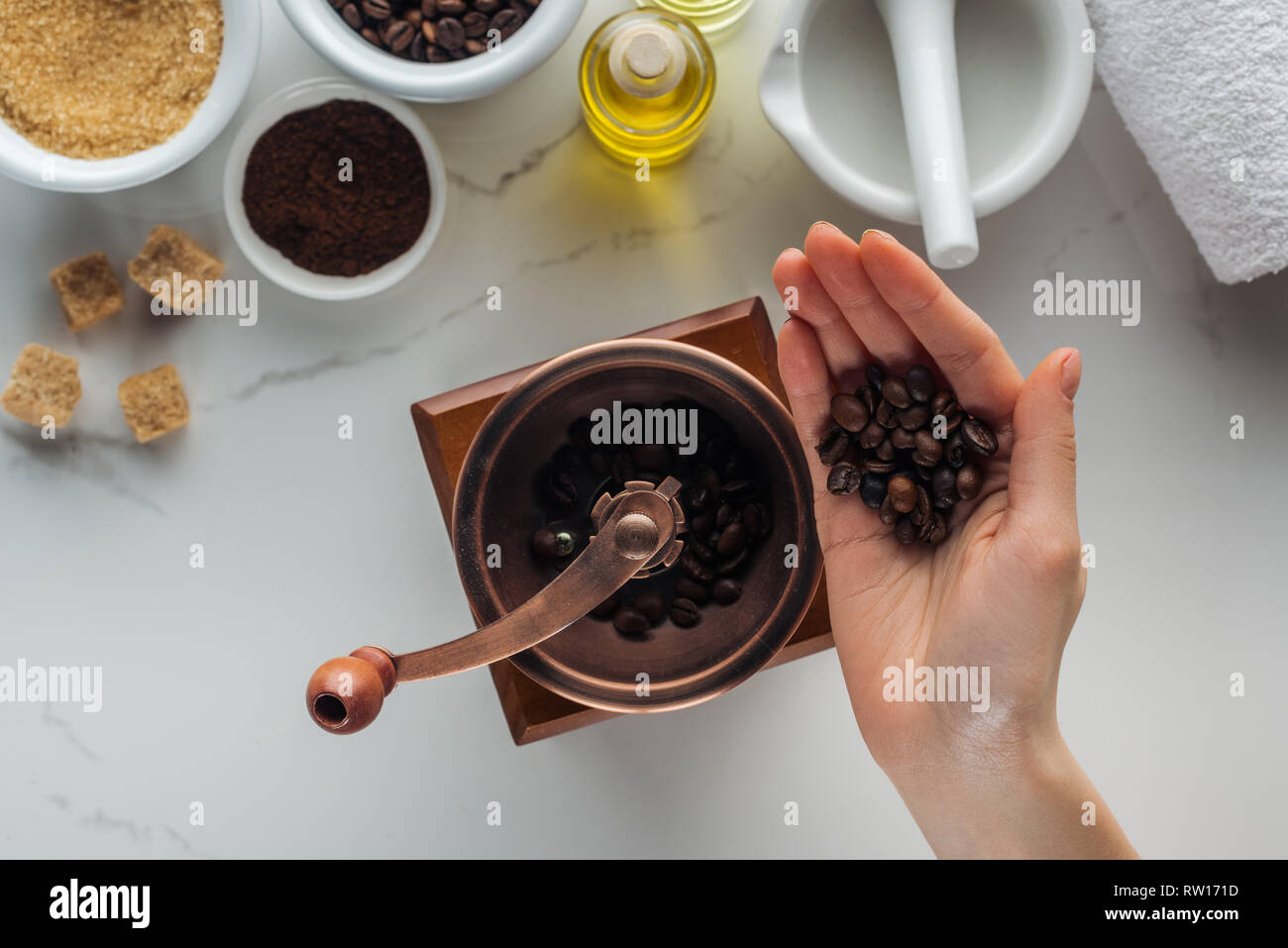 partial view of female hand with coffee grains, hand mill, pounder and ...