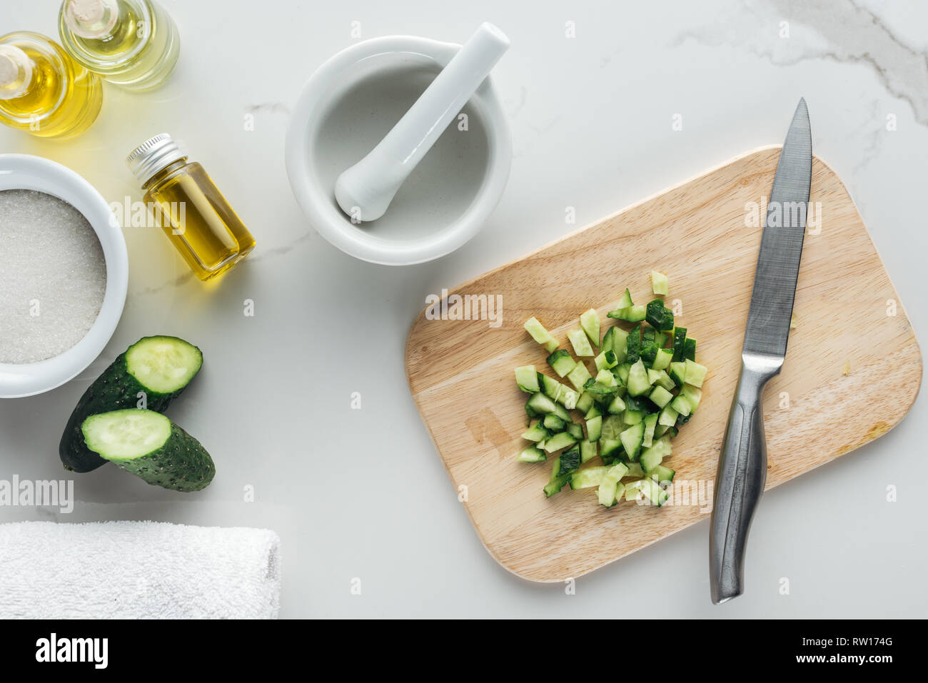 top with of wooden cutting desk with cut cucumber cubes, pounder and ...