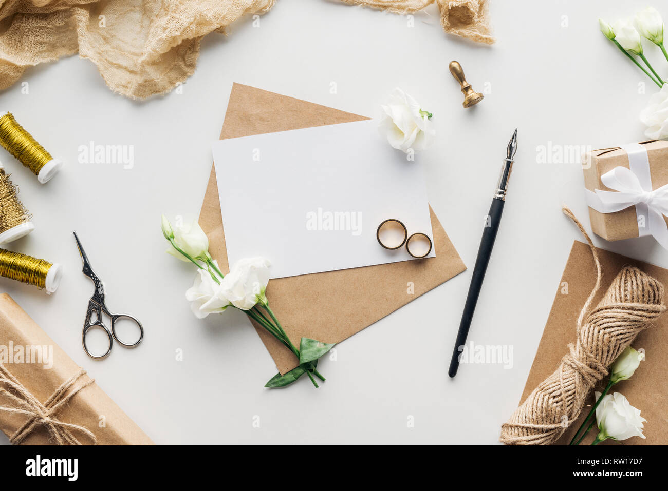 top view of empty card with envelope, ink pen, eustoma, stamp, wrapped ...