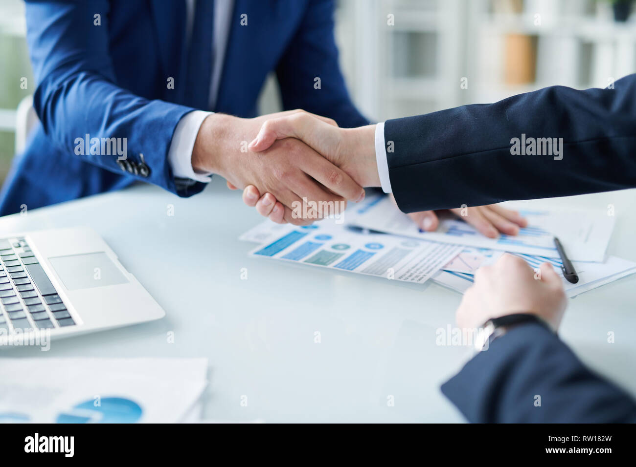 Handshaking over desk Stock Photo - Alamy