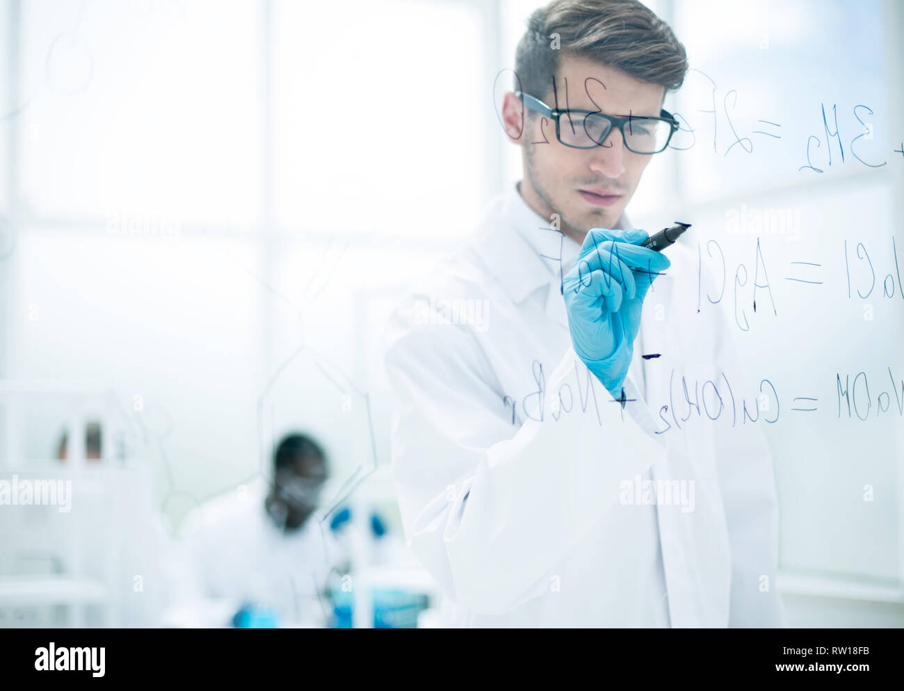 scientist making notes on the glass Board at the time of the experiment ...
