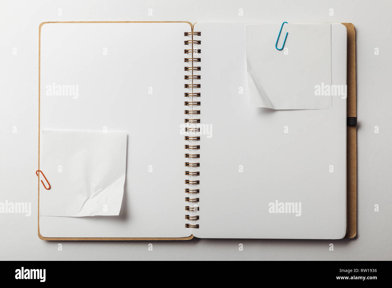 top view of opened notebook with sticky notes and paper clips on white ...