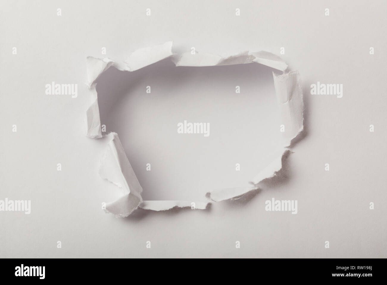 torn hole in sheet of paper on white background Stock Photo - Alamy