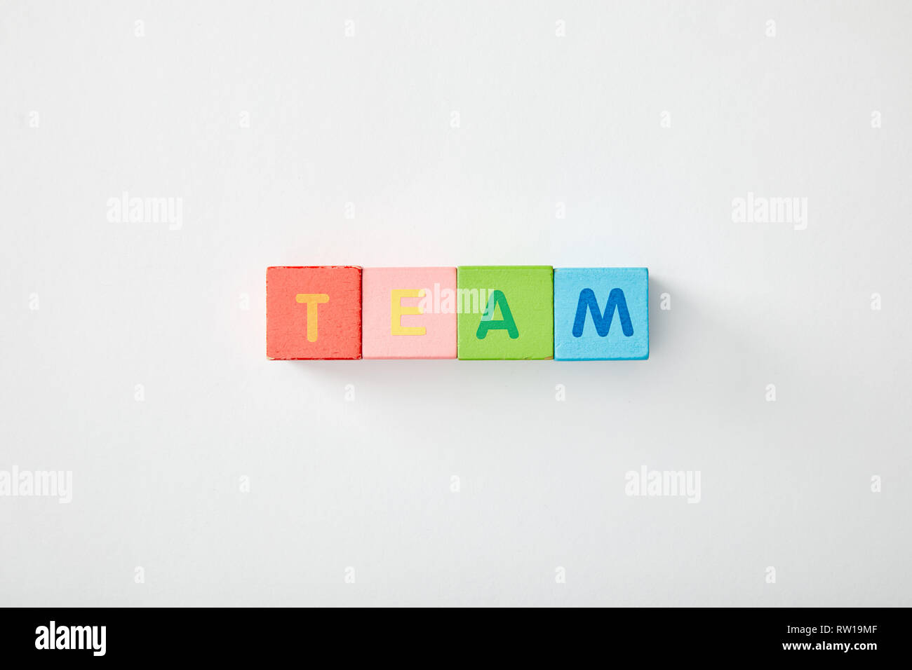 top view of team lettering made of multicolored cubes on grey ...