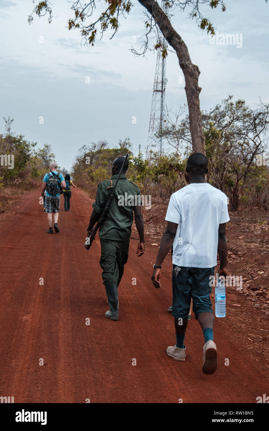 Tourists and an armed park ranger walking on a road at the Mole ...
