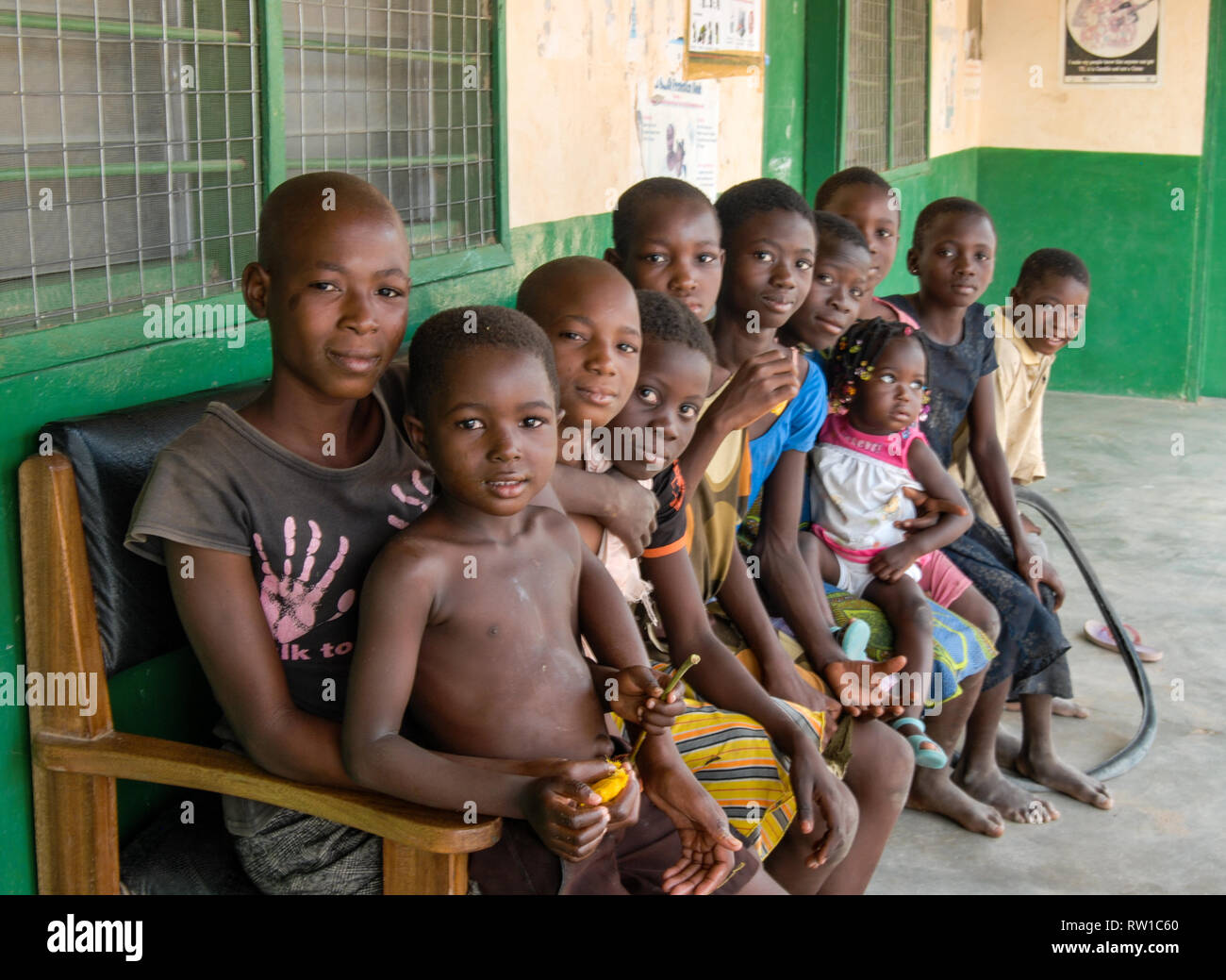 A group photo of local Ghanaian children sitting on a bench and posing ...