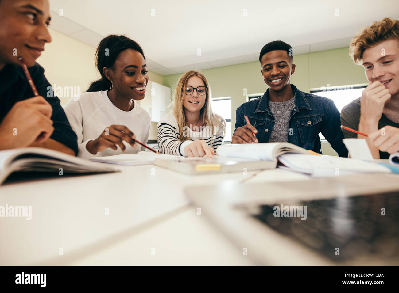 Happy young university students studying with books in college. Group ...