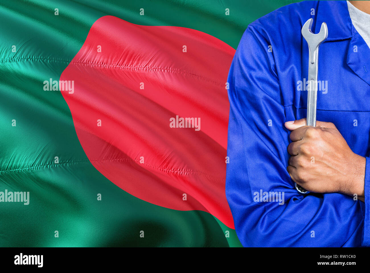 Mechanic in blue uniform is holding wrench against waving Bangladesh ...