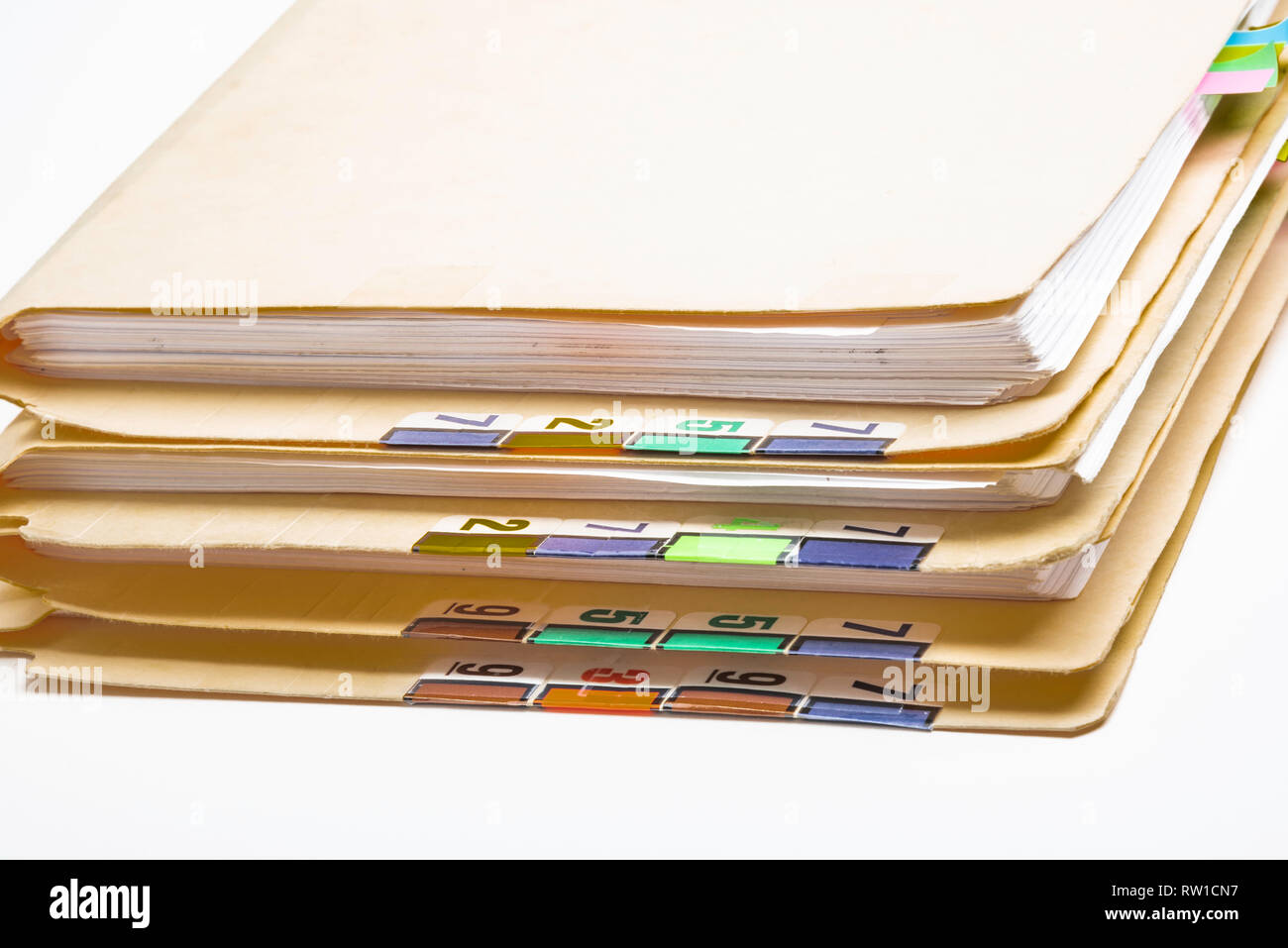A stack of patient medical records in folders with color-coded and ...