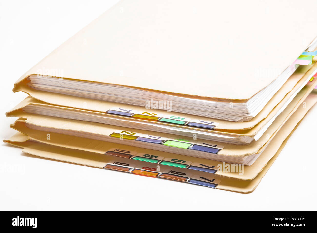 A stack of patient medical records in folders with color-coded and ...