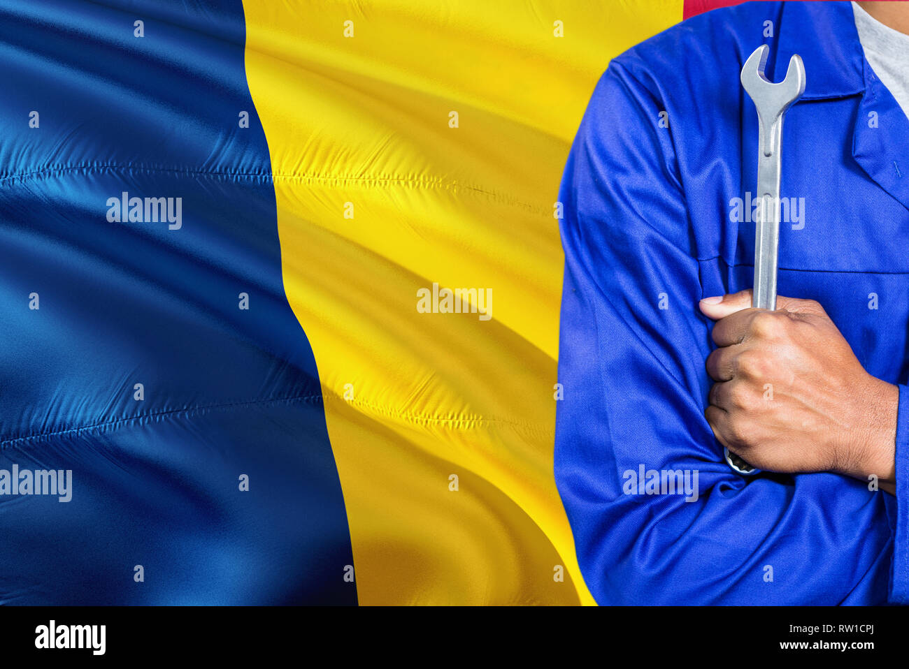 Chadian Mechanic in blue uniform is holding wrench against waving Chad ...