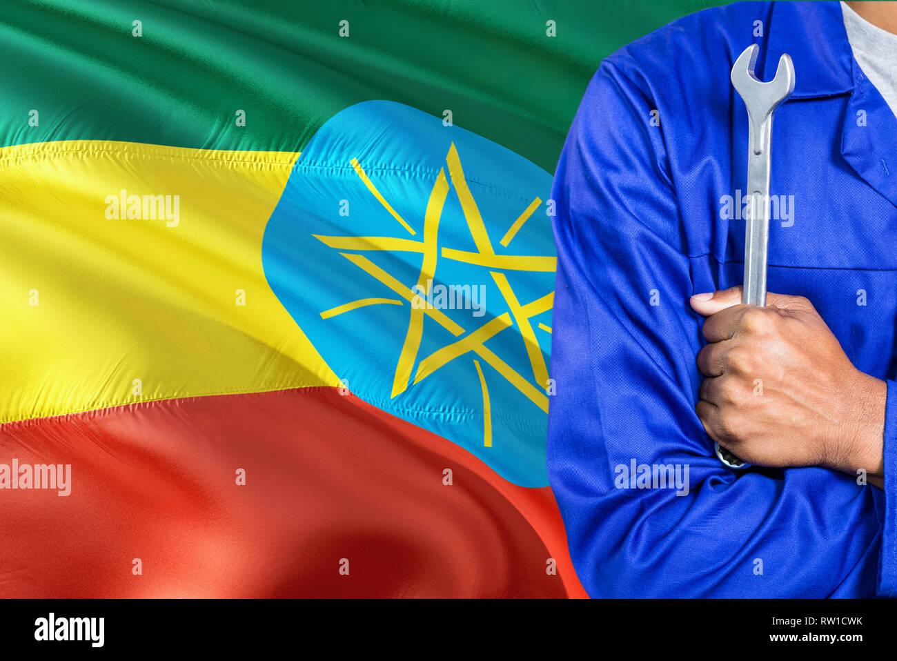 Ethiopian Mechanic in blue uniform is holding wrench against waving ...