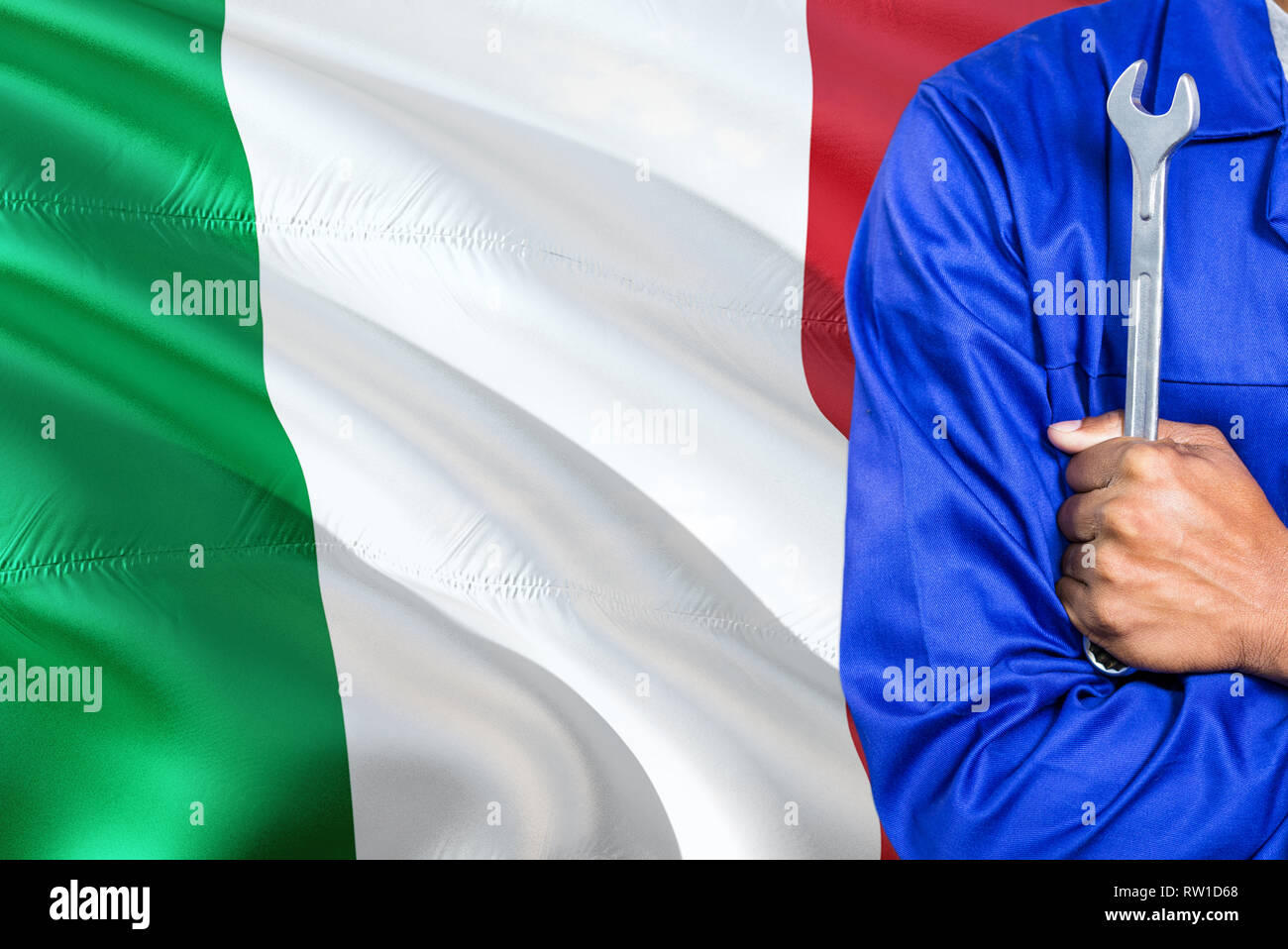 Italian Mechanic in blue uniform is holding wrench against waving Italy ...