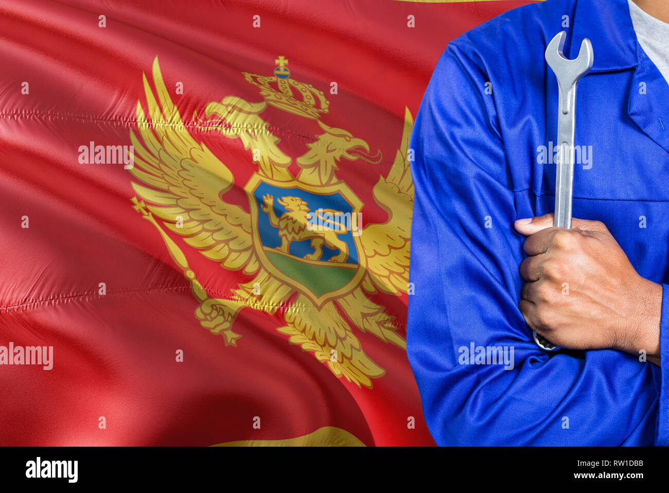 Montenegrin Mechanic in blue uniform is holding wrench against waving ...