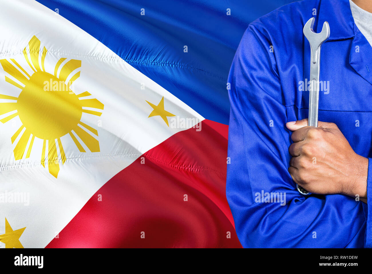 Filipino Mechanic in blue uniform is holding wrench against waving ...