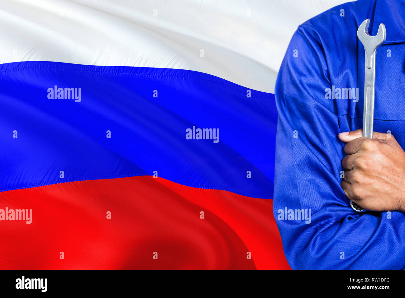 Russian Mechanic in blue uniform is holding wrench against waving ...