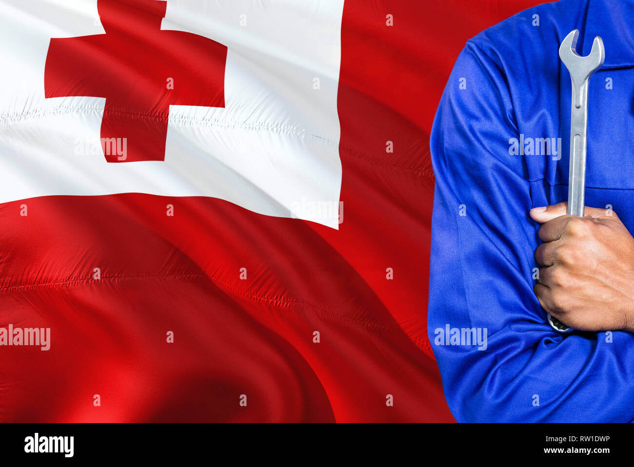 Tongan Mechanic in blue uniform is holding wrench against waving Tonga ...