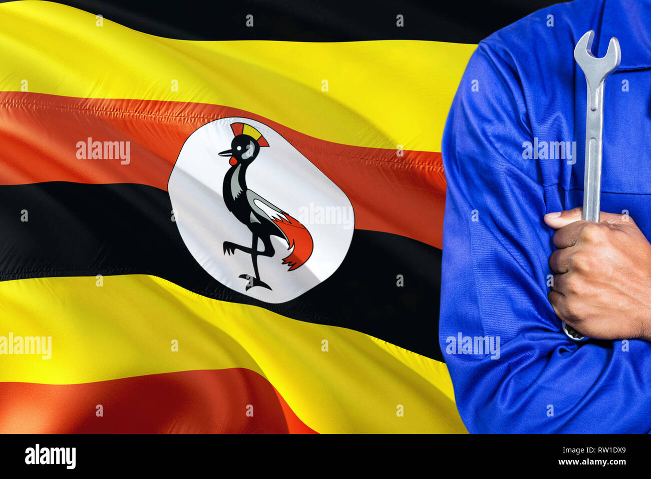 Ugandan Mechanic in blue uniform is holding wrench against waving ...