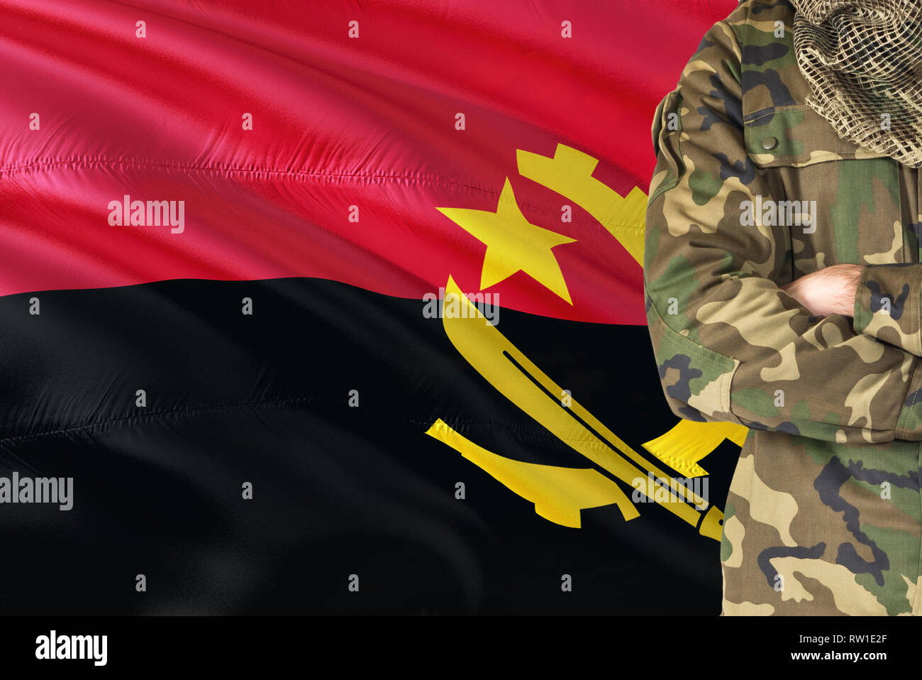 Crossed arms Angolan soldier with national waving flag on background ...