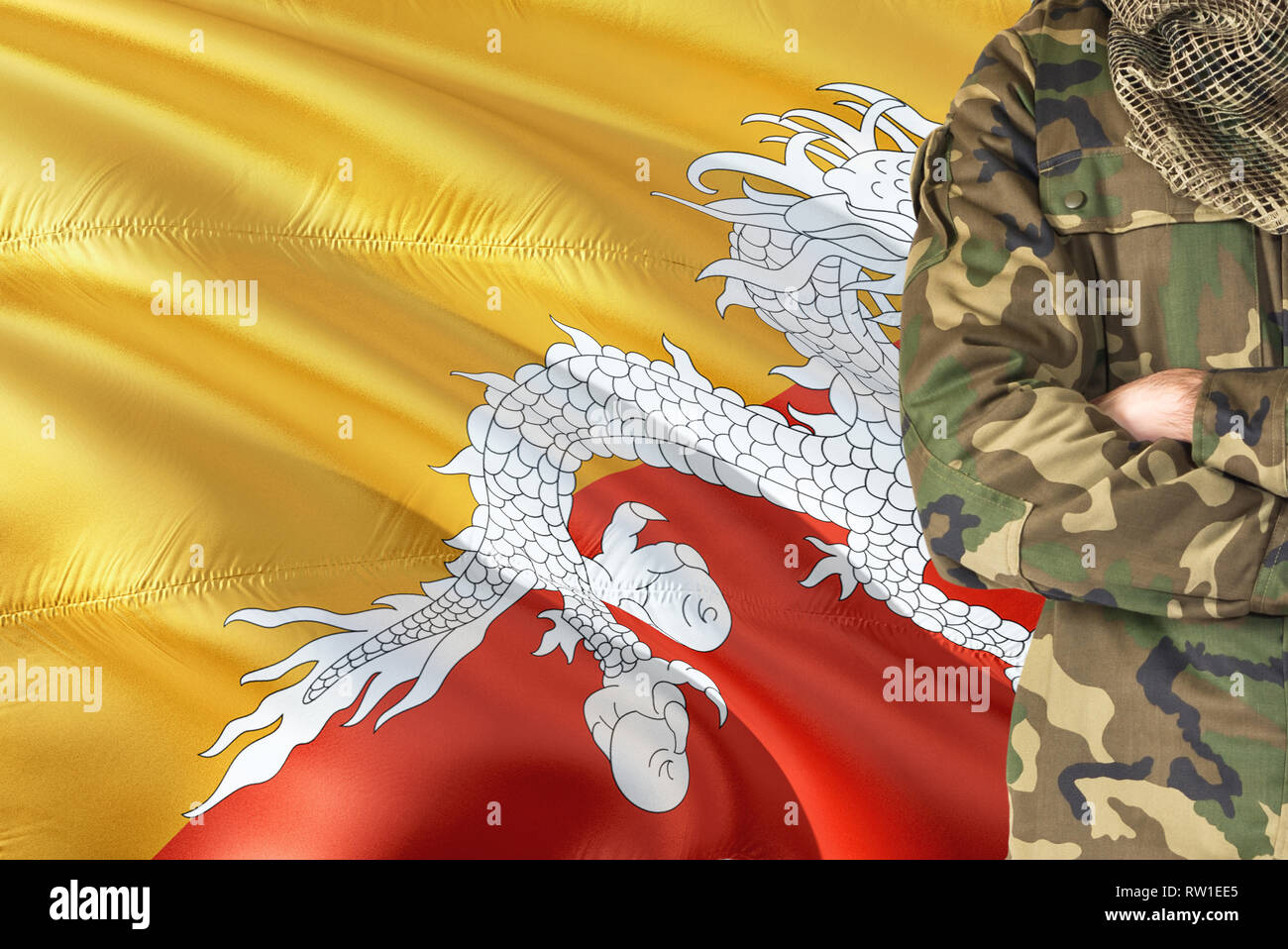 Crossed arms Bhutanese soldier with national waving flag on background ...