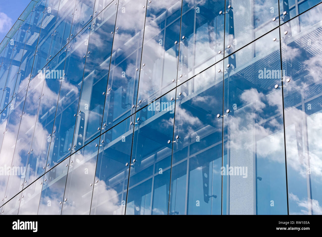 clouds reflected on glass facade wall of modern office building ...