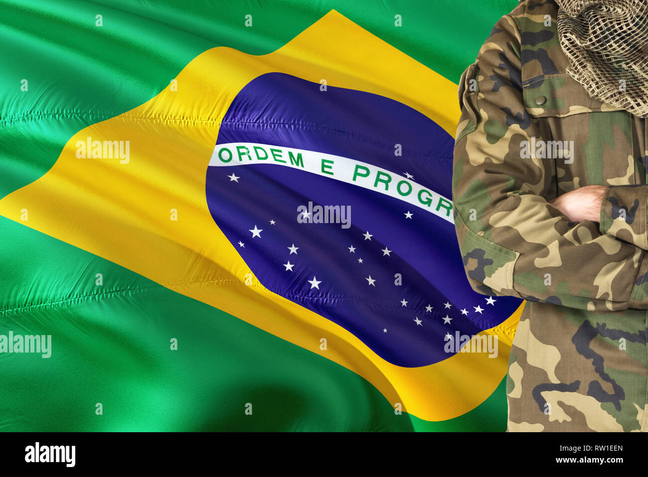 Crossed arms Brazilian soldier with national waving flag on background ...