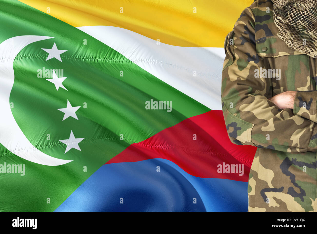 Crossed arms Comoran soldier with national waving flag on background ...
