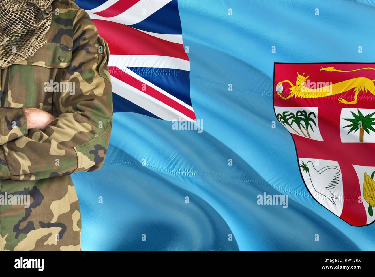 Crossed arms Fijian soldier with national waving flag on background ...