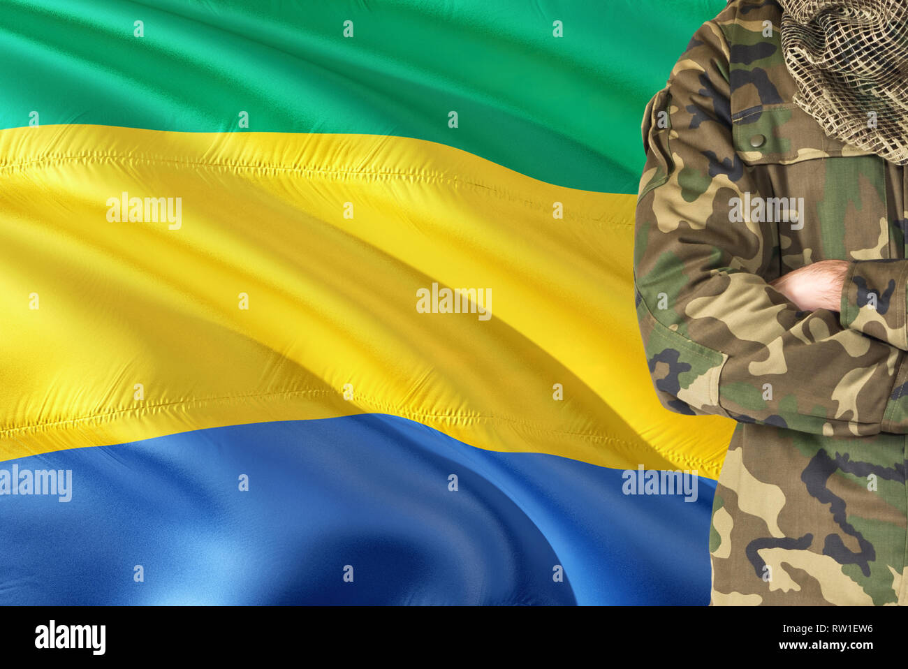 Crossed arms Gabonese soldier with national waving flag on background ...