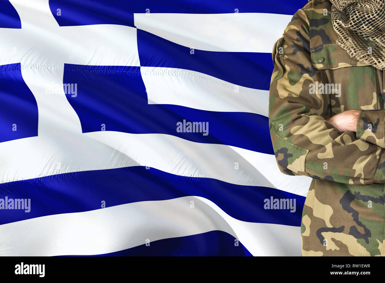 Crossed arms Greek soldier with national waving flag on background ...