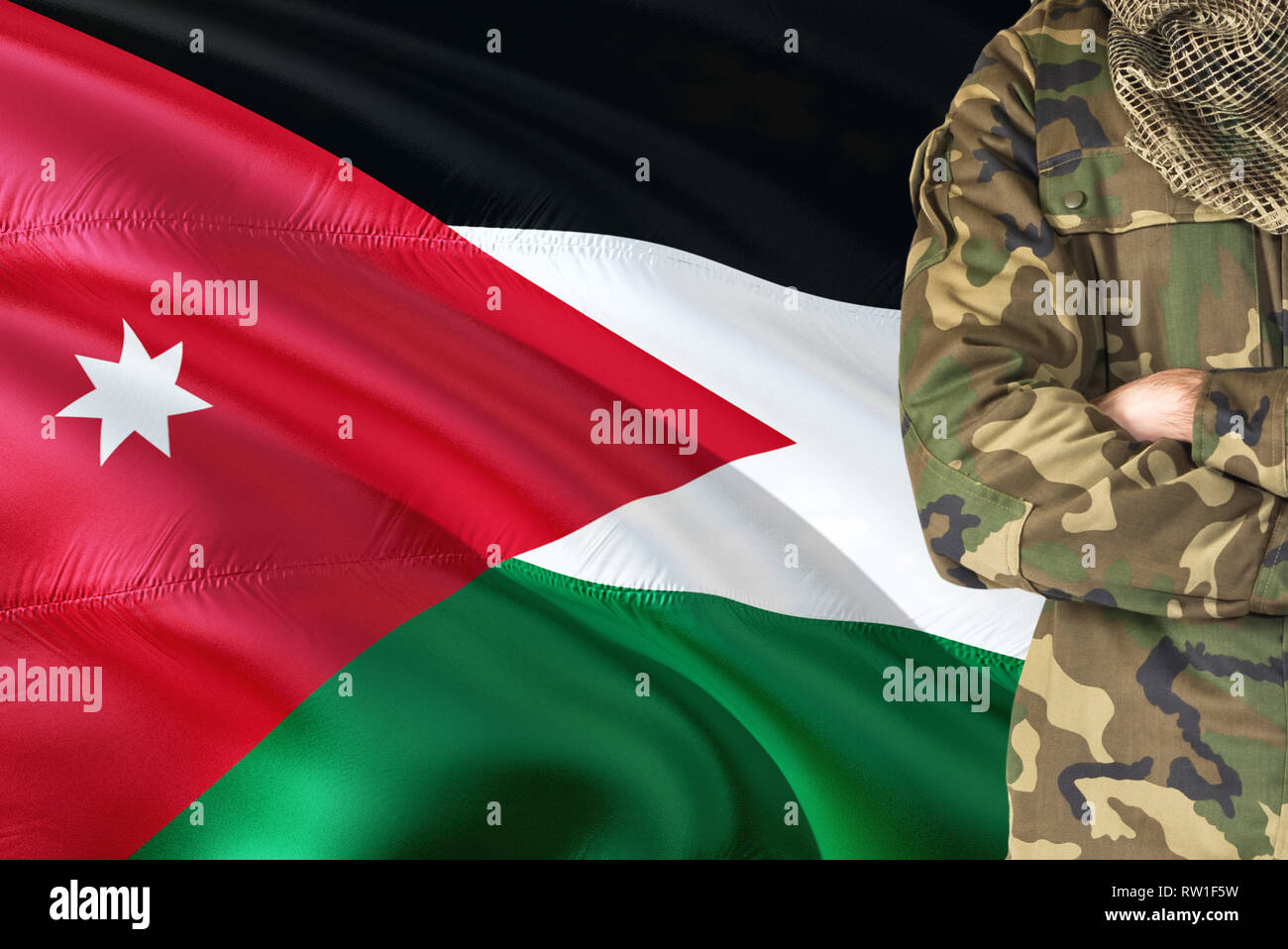 Crossed arms Jordanian soldier with national waving flag on background ...