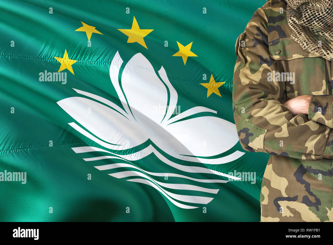Crossed arms Macau soldier with national waving flag on background ...