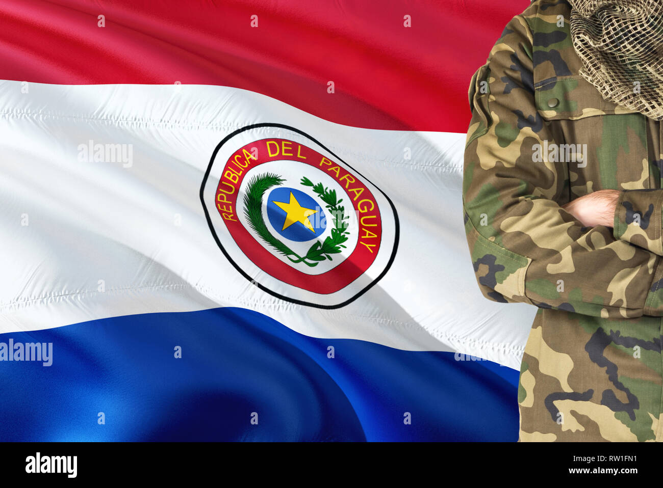 Crossed arms Paraguayan soldier with national waving flag on background ...