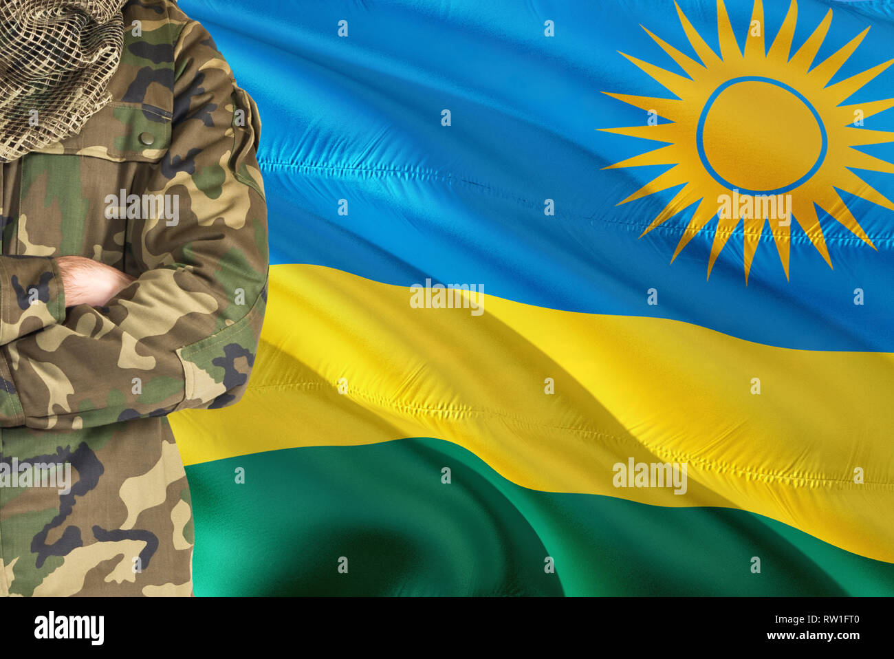 Crossed arms Rwandan soldier with national waving flag on background ...