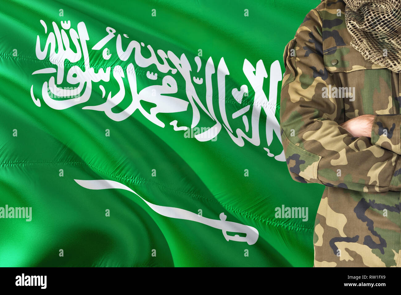 Crossed arms Saudi soldier with national waving flag on background ...