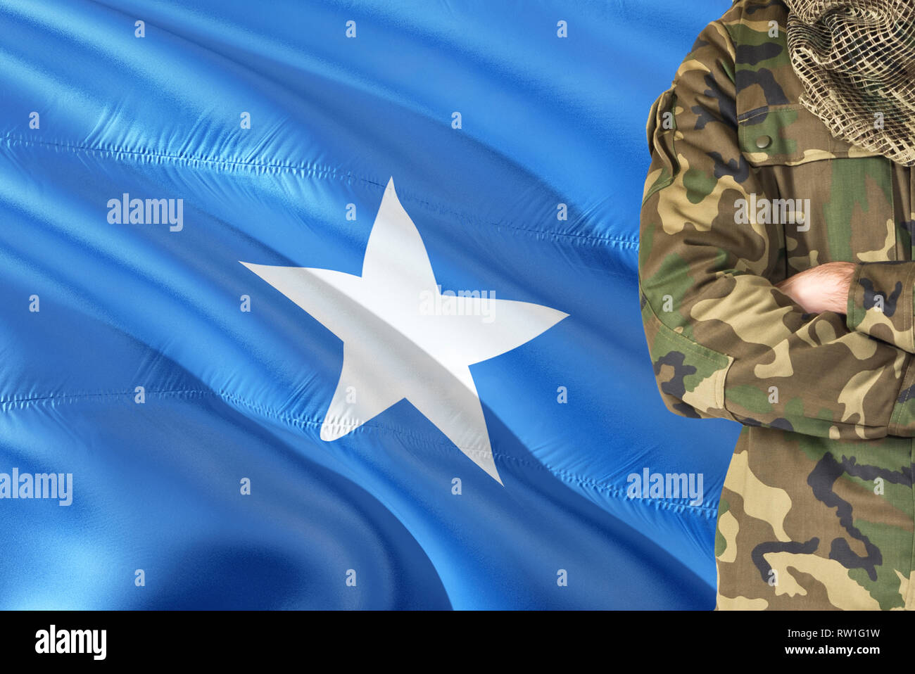 Crossed arms Somalian soldier with national waving flag on background ...