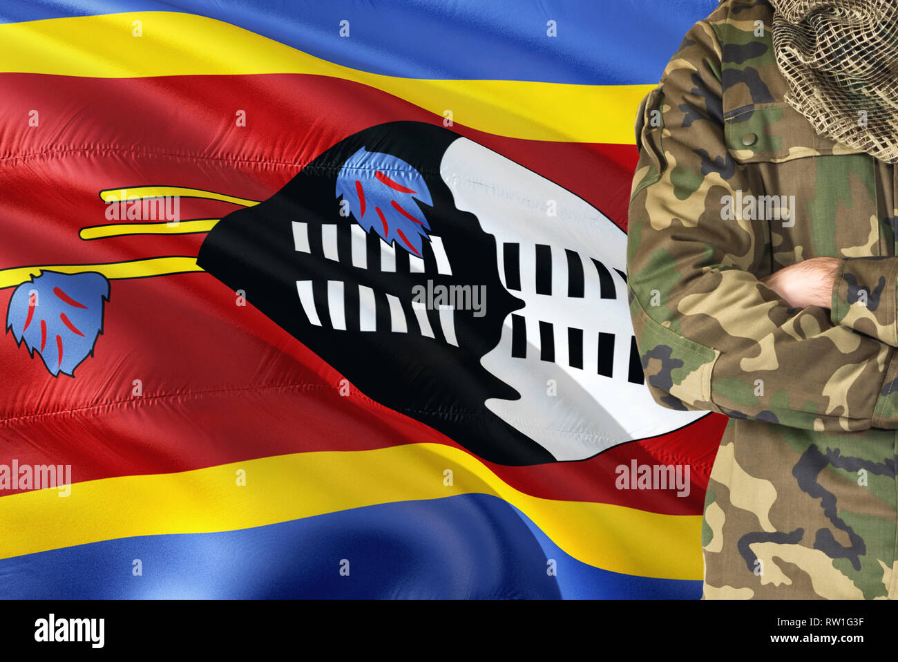 Crossed arms Swazi soldier with national waving flag on background ...