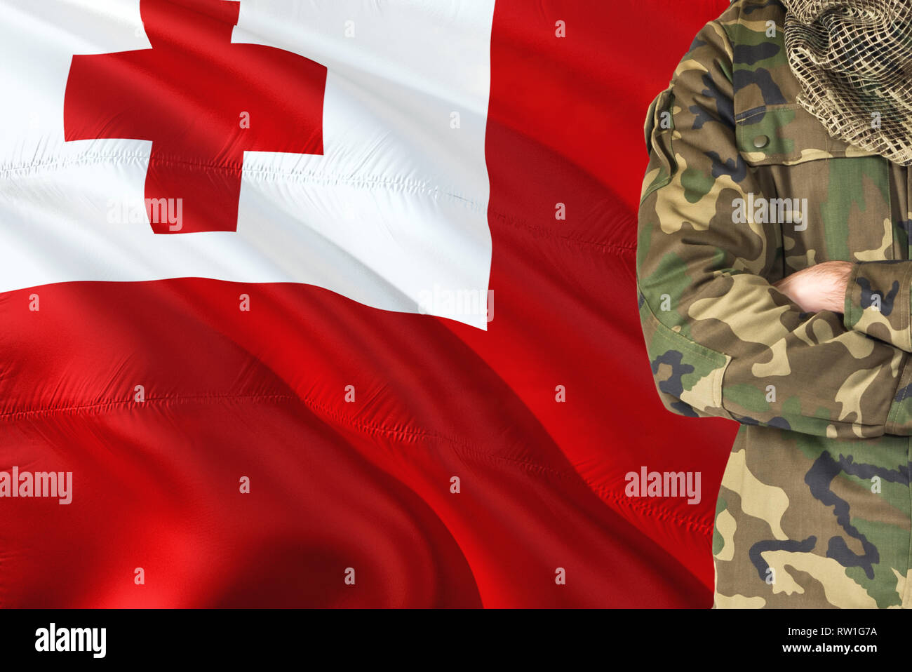 Crossed arms Tongan soldier with national waving flag on background ...