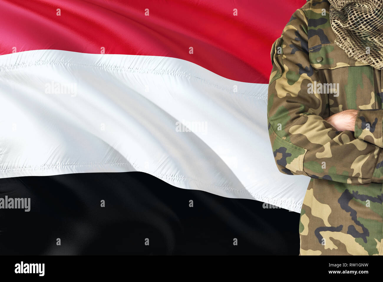 Crossed arms Yemeni soldier with national waving flag on background ...