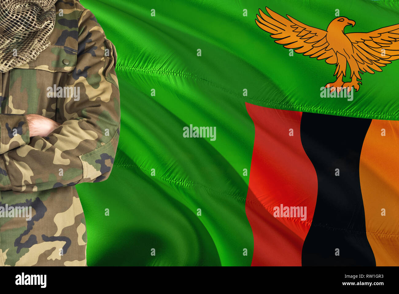 Crossed arms Zambian soldier with national waving flag on background ...