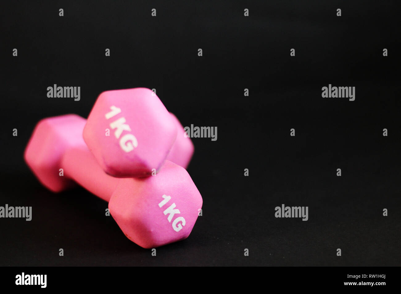 Stay fit concept - pink dumbbells, black background, free copy space ...