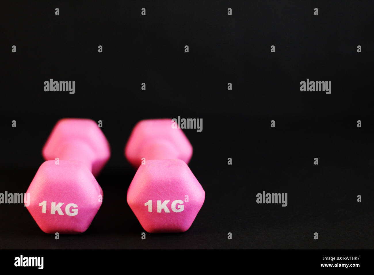 Pink dumbbells, black background, free copy space, selective focus ...