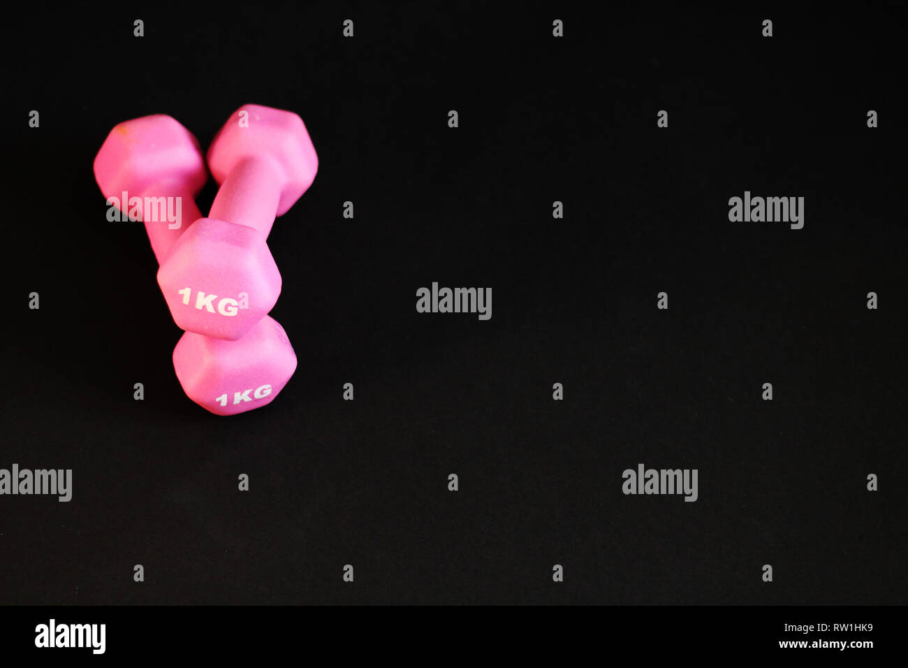 Pink dumbbells, black background, free copy space, selective focus ...